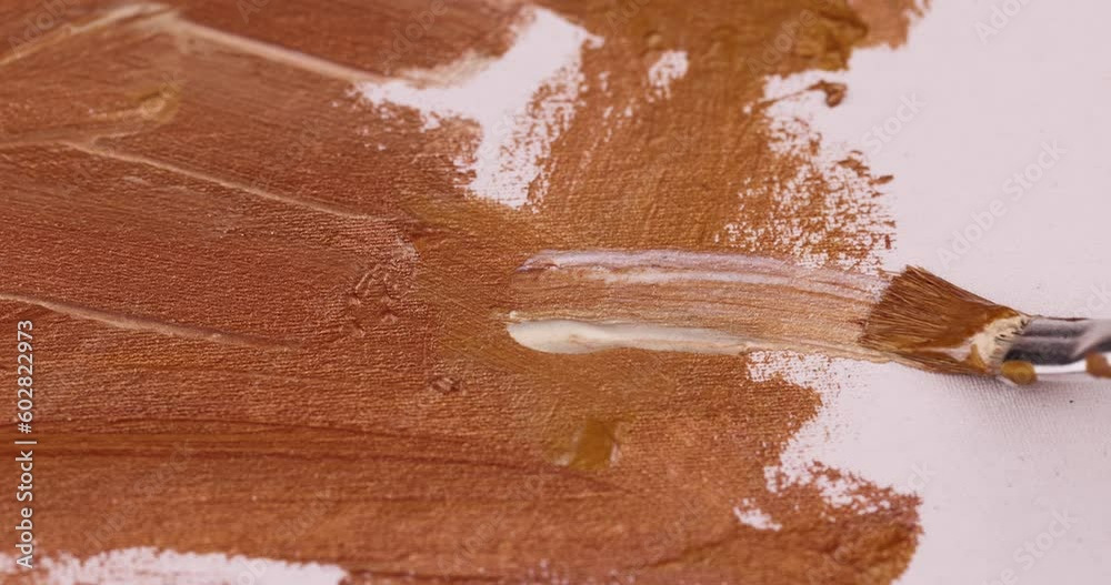 drawing lines with gold paint on canvas with an artistic brush, using ...