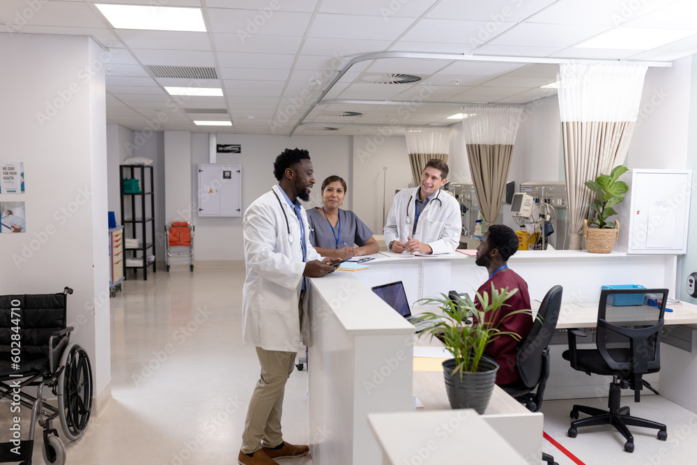 Happy diverse doctors and medical staff talking at reception desk of ...