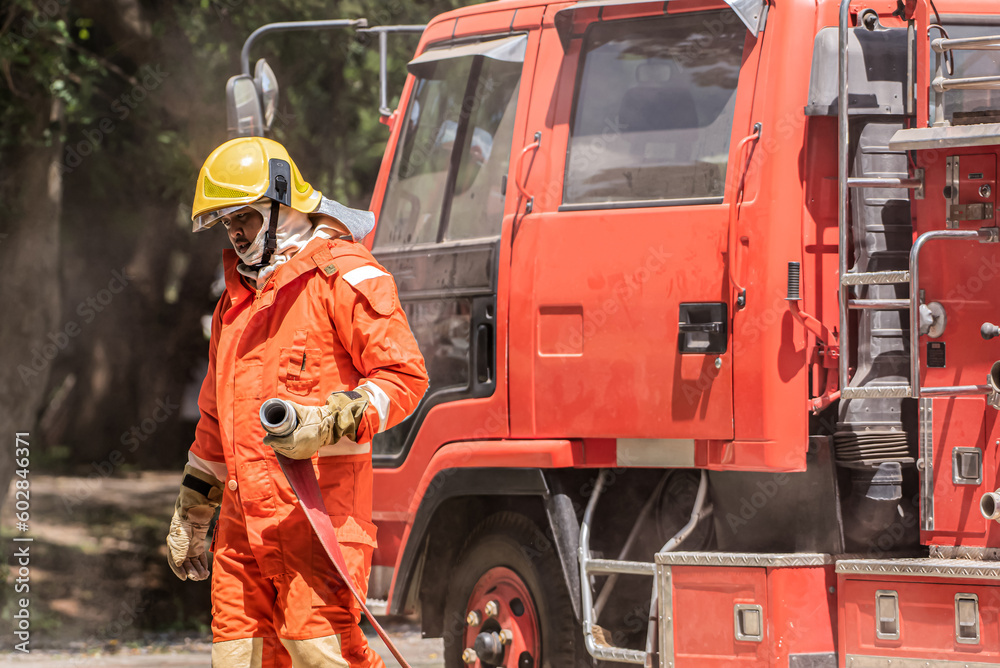 Firefighter standing next to fire truck holding fire hose with ...