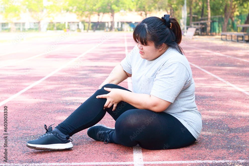 Fat Asian woman injured from jogging Sitting on the floor, holding the ...
