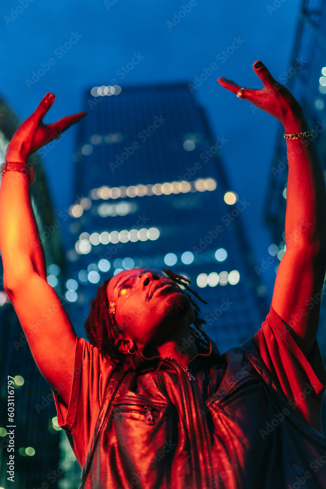 Excited young black man raising hands in lights Stock Photo | Adobe Stock