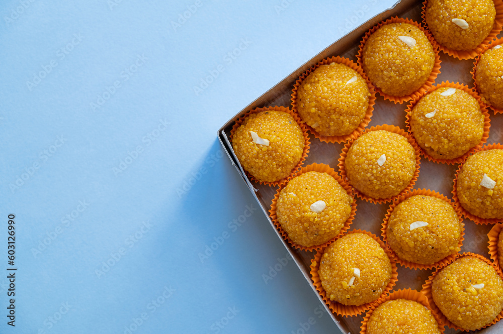 Laddu sweets kept in the box packing with pale blue background and copy ...