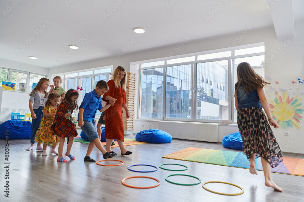 Small nursery school children with female teacher on floor indoors in ...