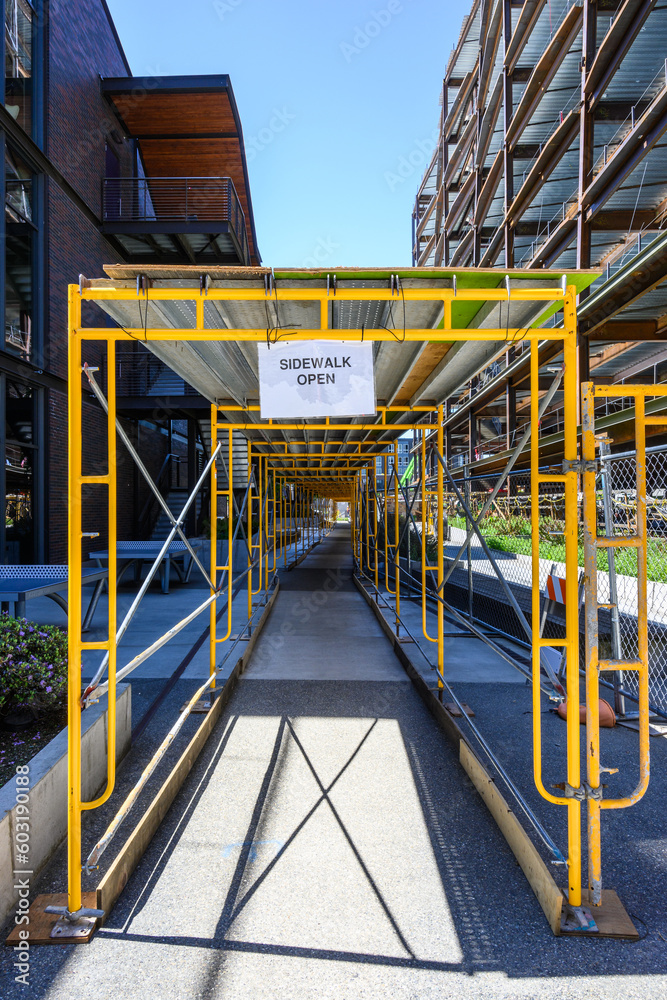 City construction site, walkway covered with scaffolding and roof for ...