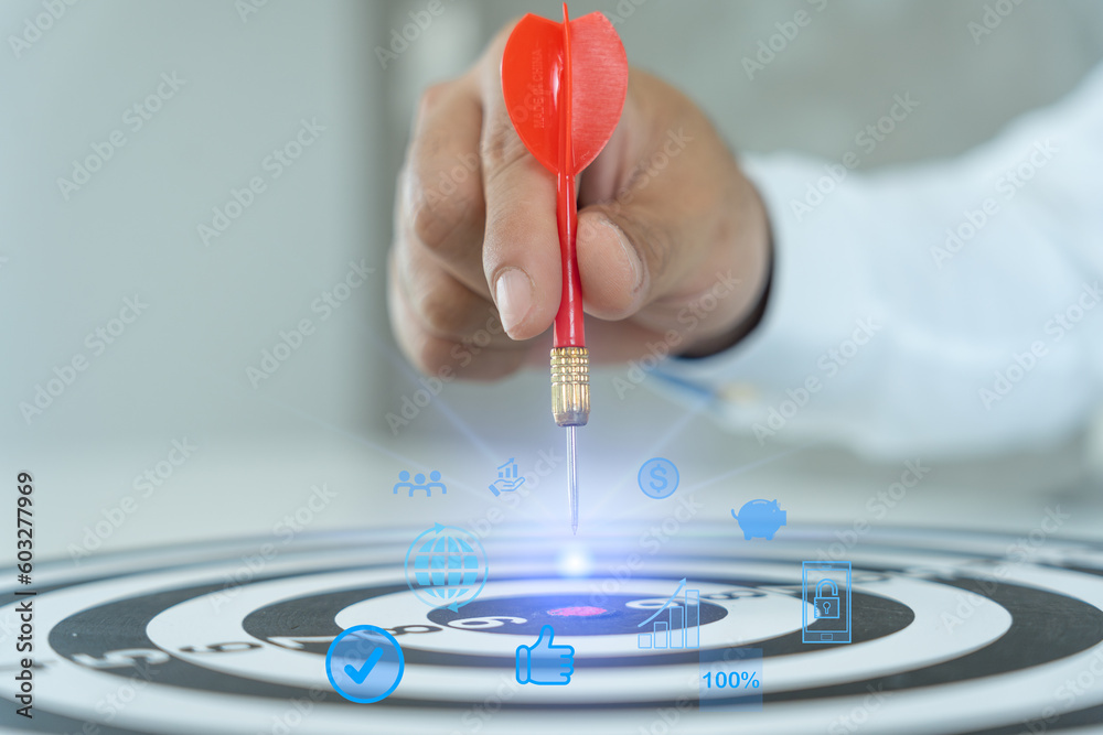 Businessman set goals for work. Hand holding a dart aiming at the ...