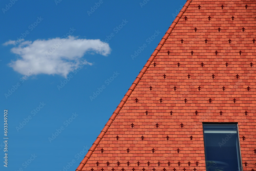 clay tile roof with steep slope in red brown color. roof window or ...