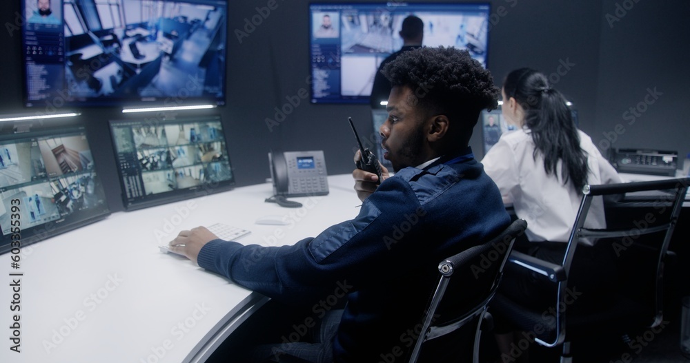 Multi ethnic security operators control CCTV cameras with AI facial ...