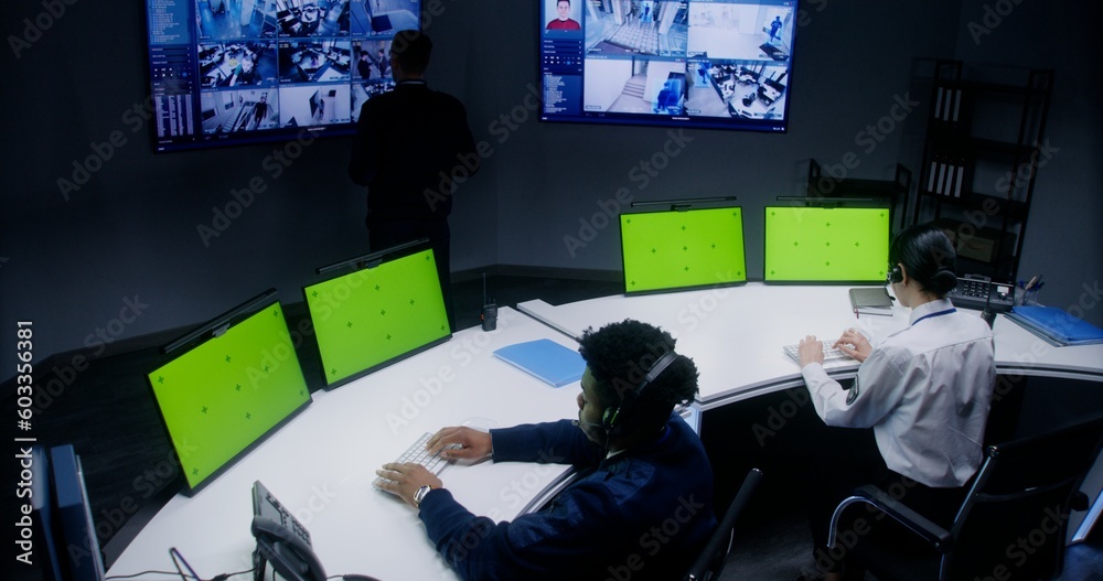 Multiracial officers control security cameras. Workers in monitoring ...