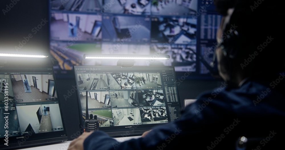 African American officer in headset controls security cameras with AI ...