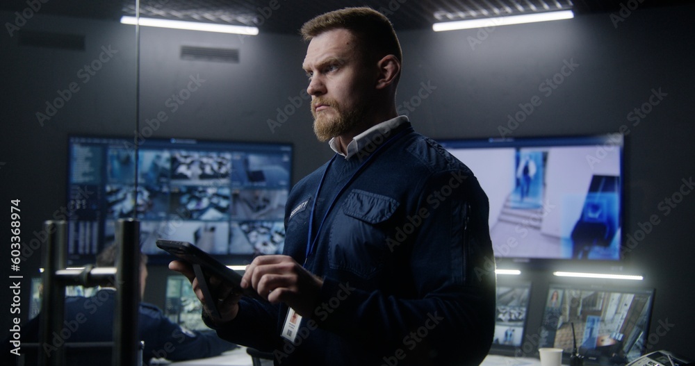 Male security officer controls CCTV cameras in police surveillance ...