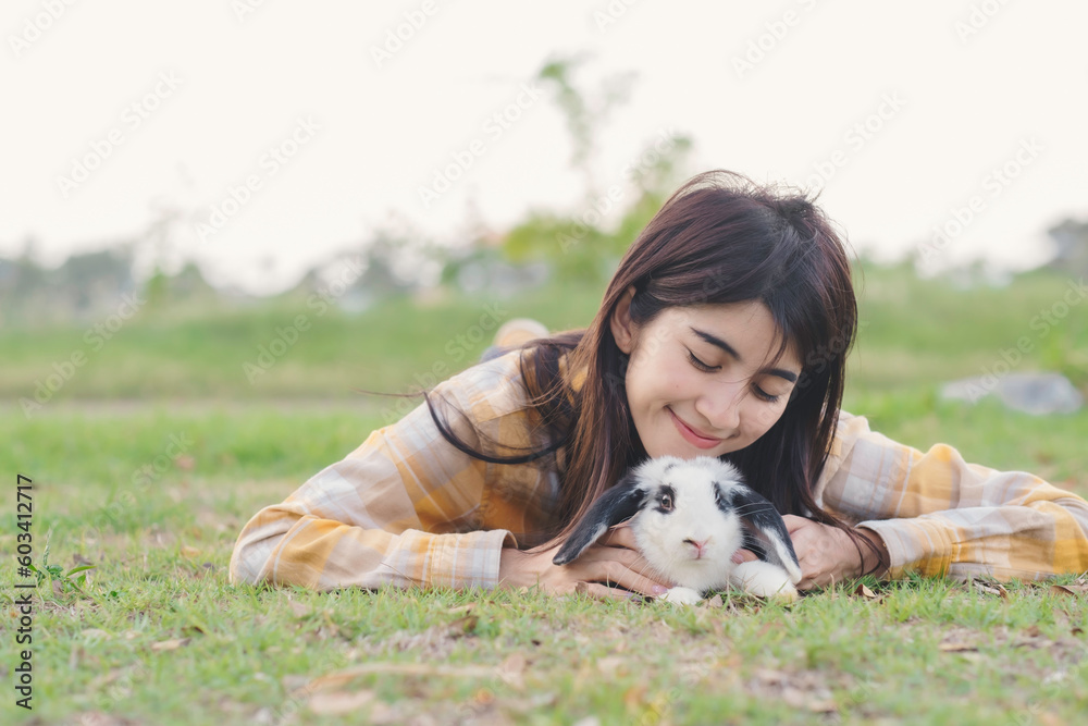 Cute and flufy white rabbit sitting on green grass floor in woman ...