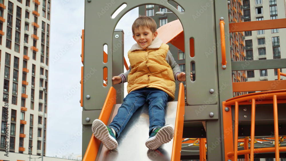 Slow motion of happy cheerful boy sliding down the slide at new ...