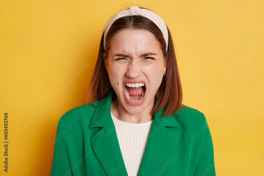Angry despair woman wearing green jacket standing isolated over yellow ...