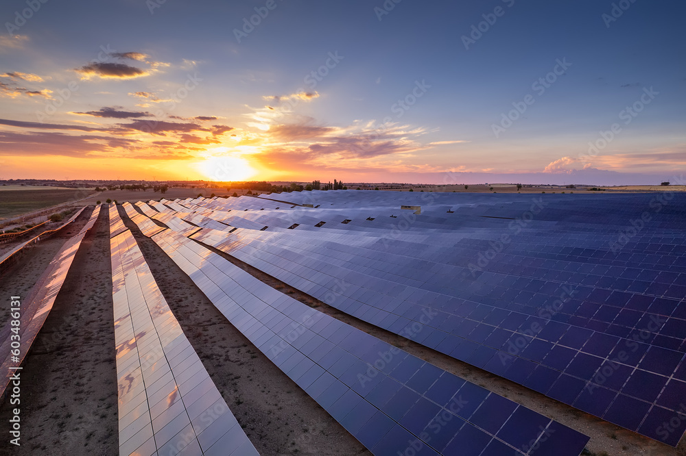 Aerial Close-Up View of a solar power plant with sunset reflection on ...