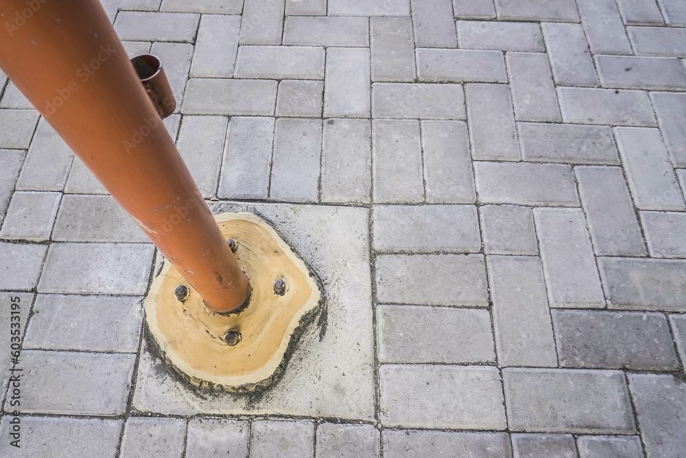 Metal pillar fastened to block paving with anchor bolts and nuts ...