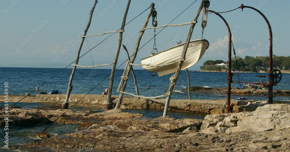 Boats hanging from traditional wooden cranes in Savudrija, Croatia ...