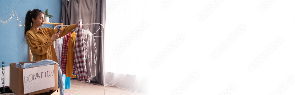 Young woman choosing clothes for donation at home taking photo of shirt ...