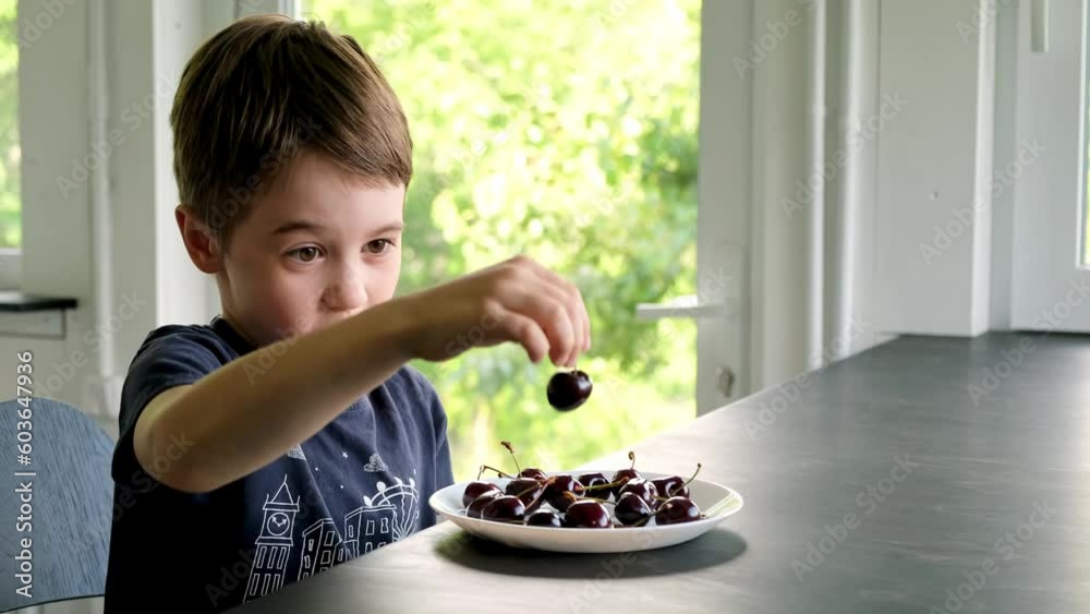 6 year cute little preschool boy eating large ripe cherries. Happy ...
