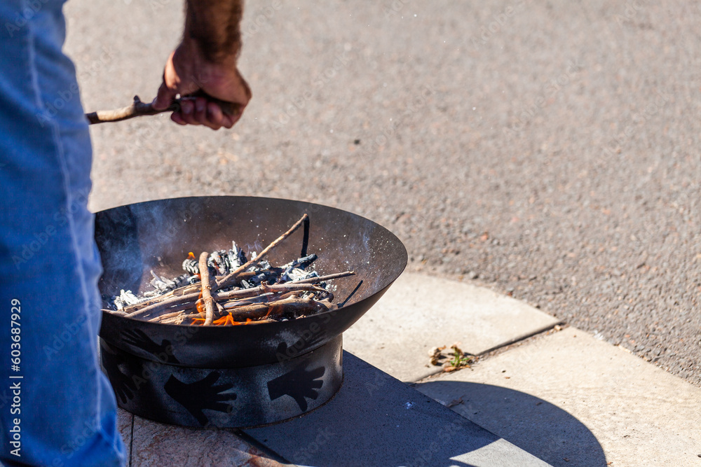 Aboriginal elder putting sticks in fire pit for smoking ceremony during ...