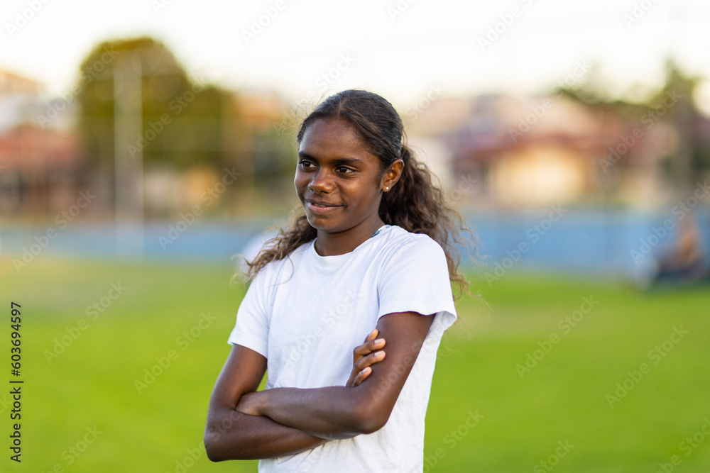 one aboriginal girl standing with arms crossed with blurry background ...