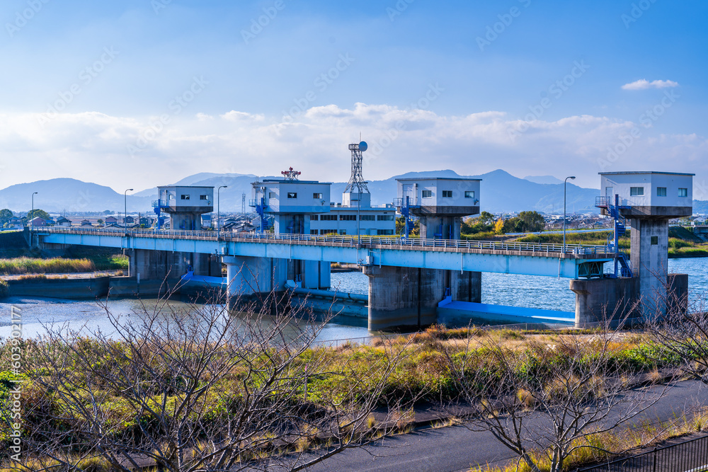 秋晴れ光芒を浴びている森林公園周辺の堤防風景 Embankment scenery around the forest park bathed ...