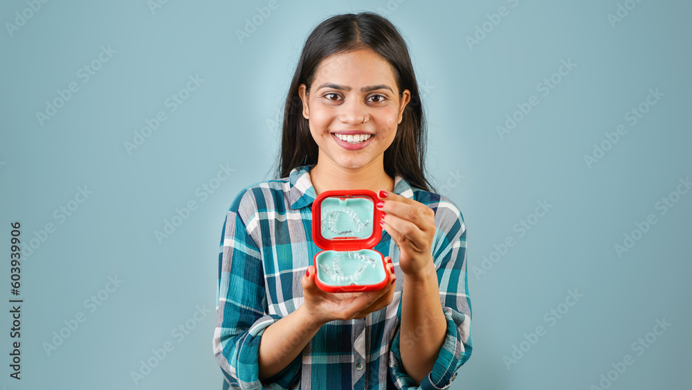 Young Asian Indian woman holding removable invisible aligner, also ...