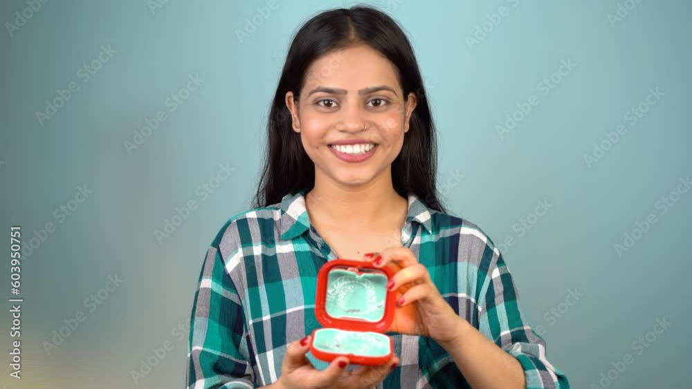 Young Asian Indian woman holding removable invisible aligner, also ...