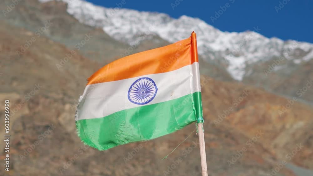 Shot of Indian flag waving in front of the snow covered mountains of ...