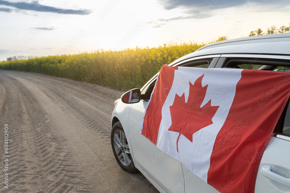 Canadian flag hanging on side of car against backdrop of setting sun ...