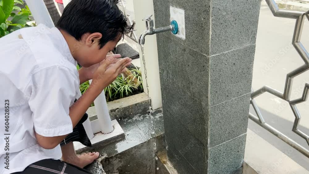 Muslim boy take ablution by washing face following procedure and ...