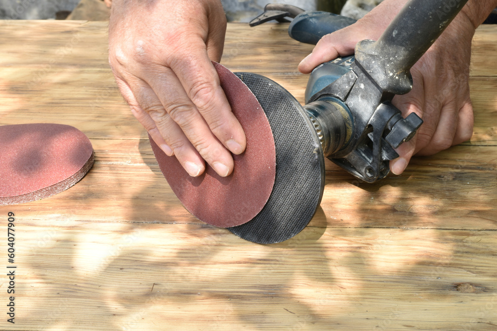 The man's hand is fixing a grinding wheel made of sandpaper on a ...