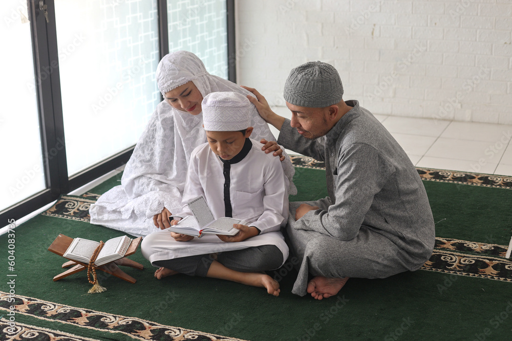 Asian Muslim family parents with children in mosque reading Quran and ...