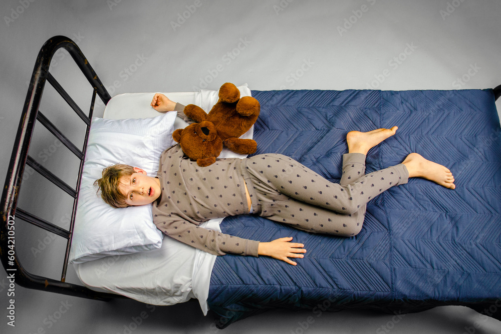 Scared boy lying in bed looking up at something scary in the air above ...
