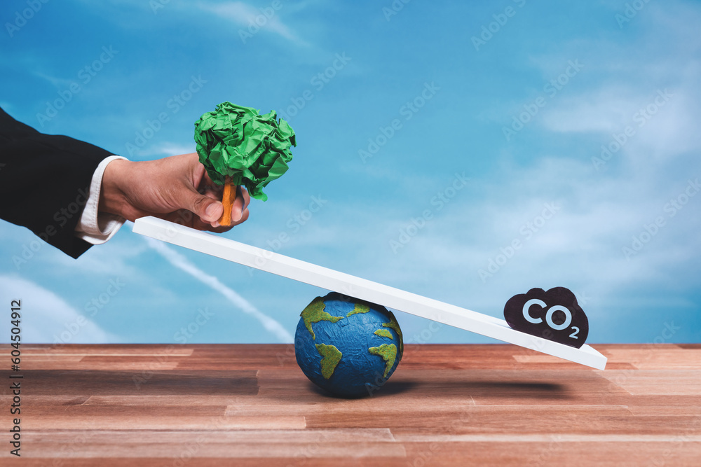Businessman hold a paper tree on scale against CO2 symbol, promoting ...