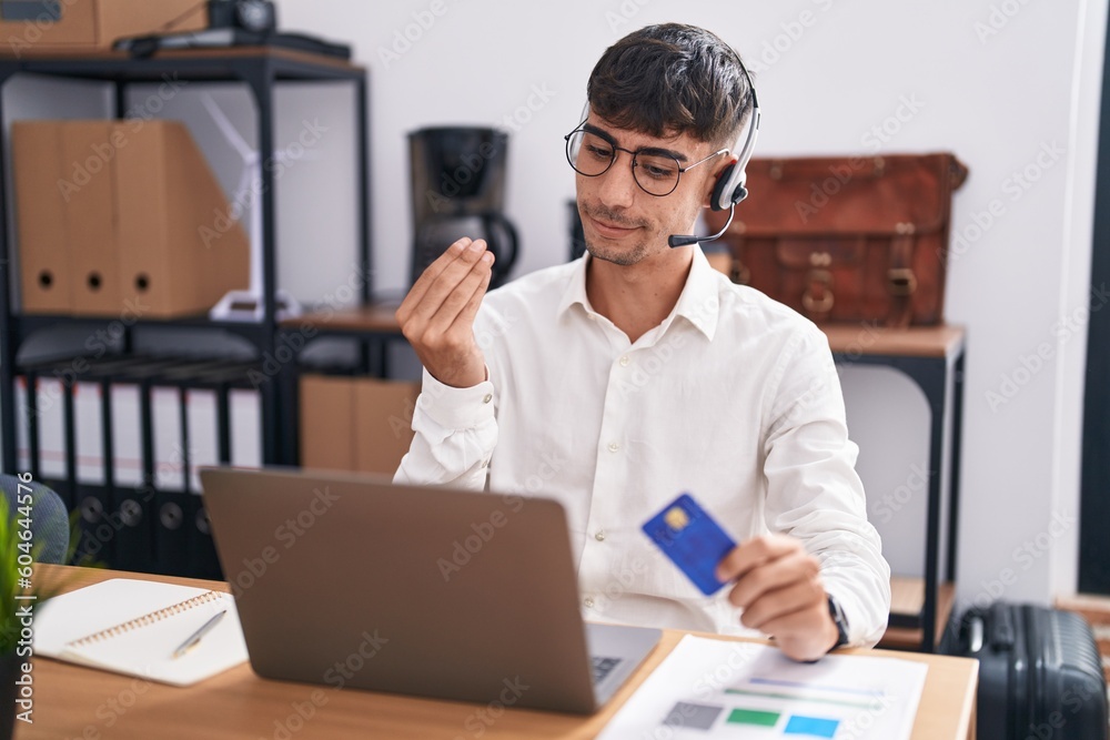 Young hispanic man working using computer laptop holding credit card ...