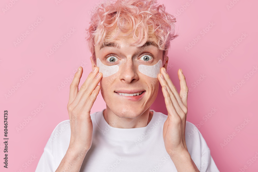 Portrait of handsome shocked European man bites lips applies beauty ...