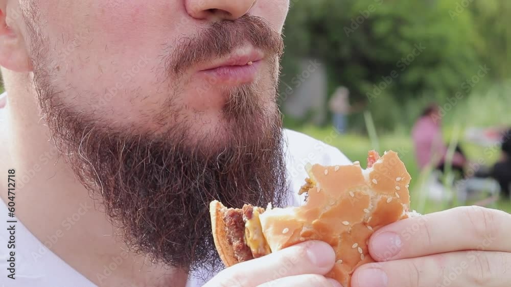 Eat a burger. Close-up male face eating a cheeseburger. Hungry young ...