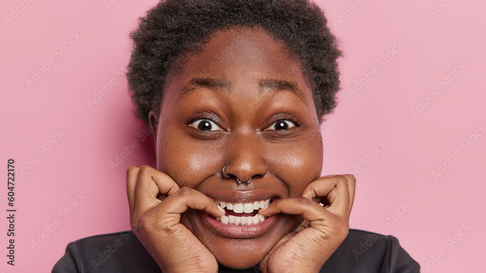 Close up shot of nervous dark skinned woman bites fingers haas worried ...