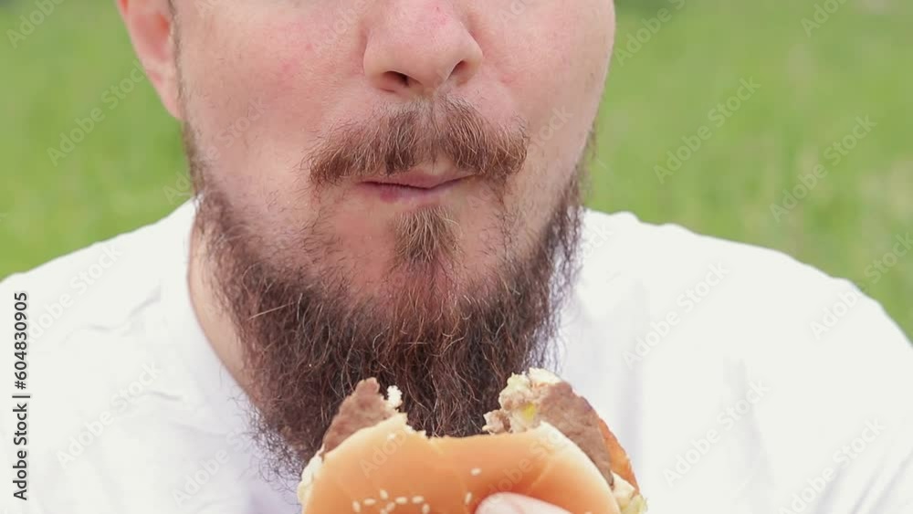 Eat a burger. Close-up male face eating a big burger. Hungry young man ...