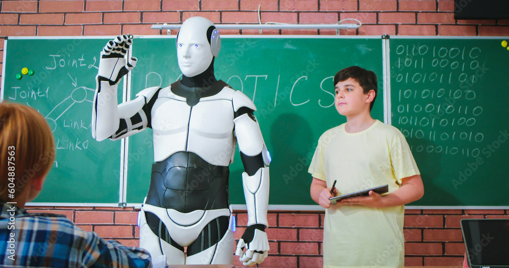 Caucasian teen schoolboy shaking hands with robot at blackboard in ...