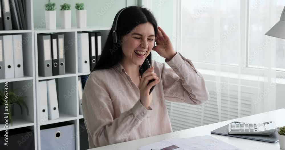 Joyful businesswoman wearing wireless headphones, listening to music ...