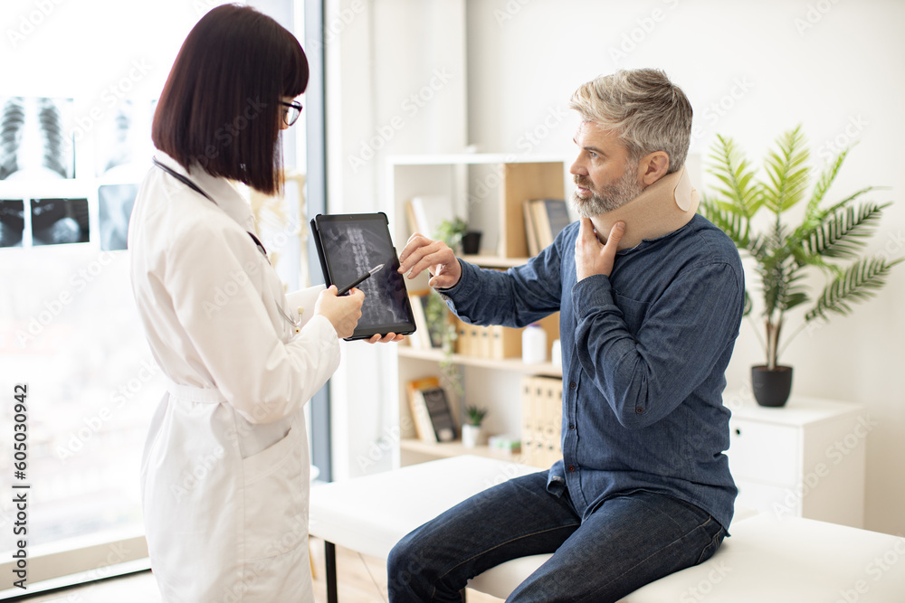 Caucasian lady holding tablet with CT scan image on screen while ...