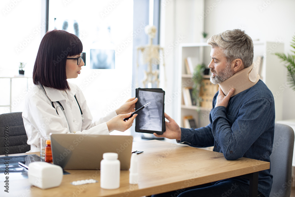 Female doctor with stethoscope and male patient in neck brace sitting ...