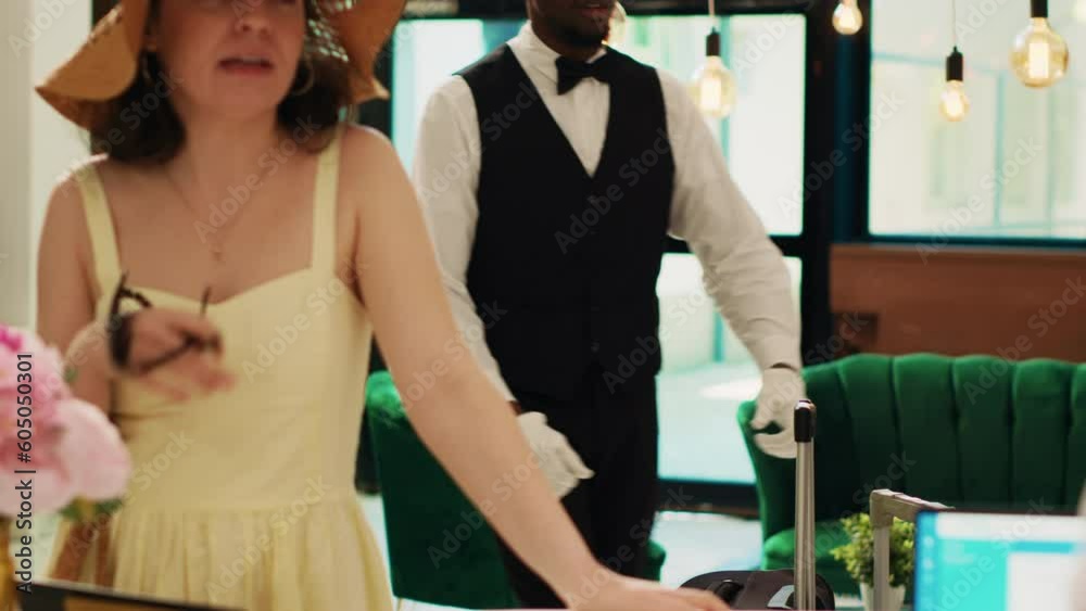 Guest arriving at exotic hotel lobby, approaching reception desk to do ...