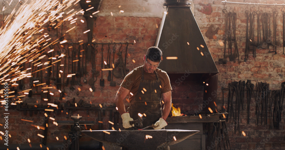 Hammer, anvil and sparks with a man at work in a forge for metal work ...