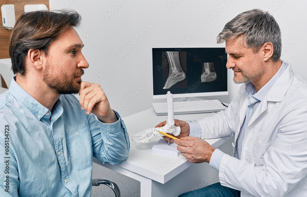 Orthopedic doctor consulting adult man with leg injury and explaining ...