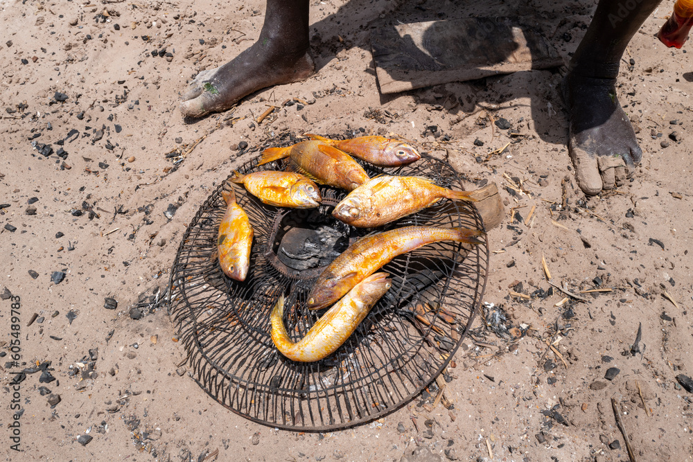 un pêcheur fait grillé ses poissons sur la plage du port de pêche de la ...