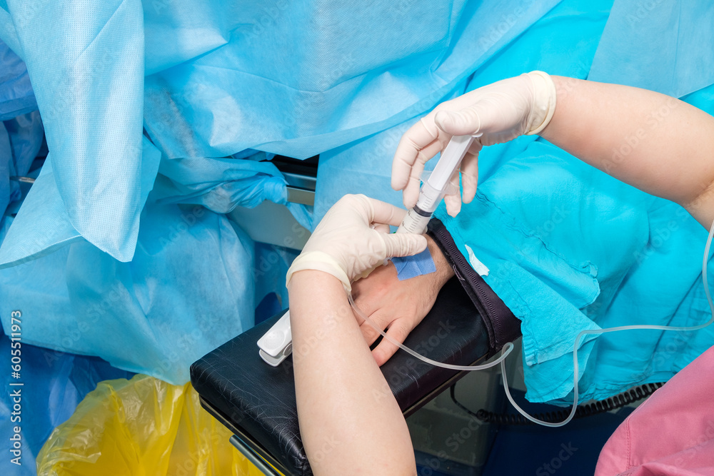 The doctor injects anesthesia with a syringe into the arm of a patient ...