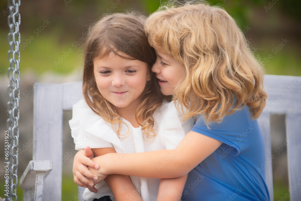 Little boy and girl best friends hugging. Kids kissing each other with love at summer park ...