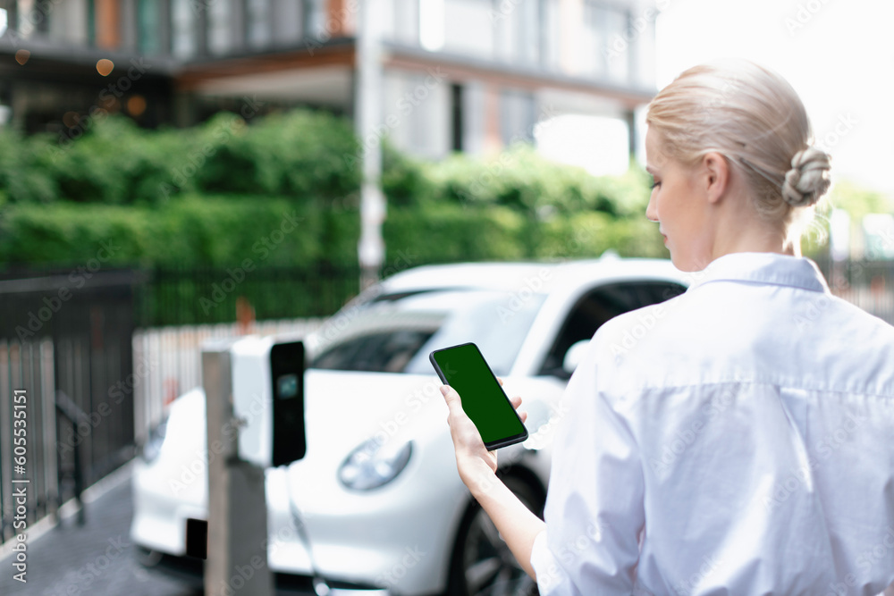 Suit-clad progressive businesswoman look at EV car's battery status ...